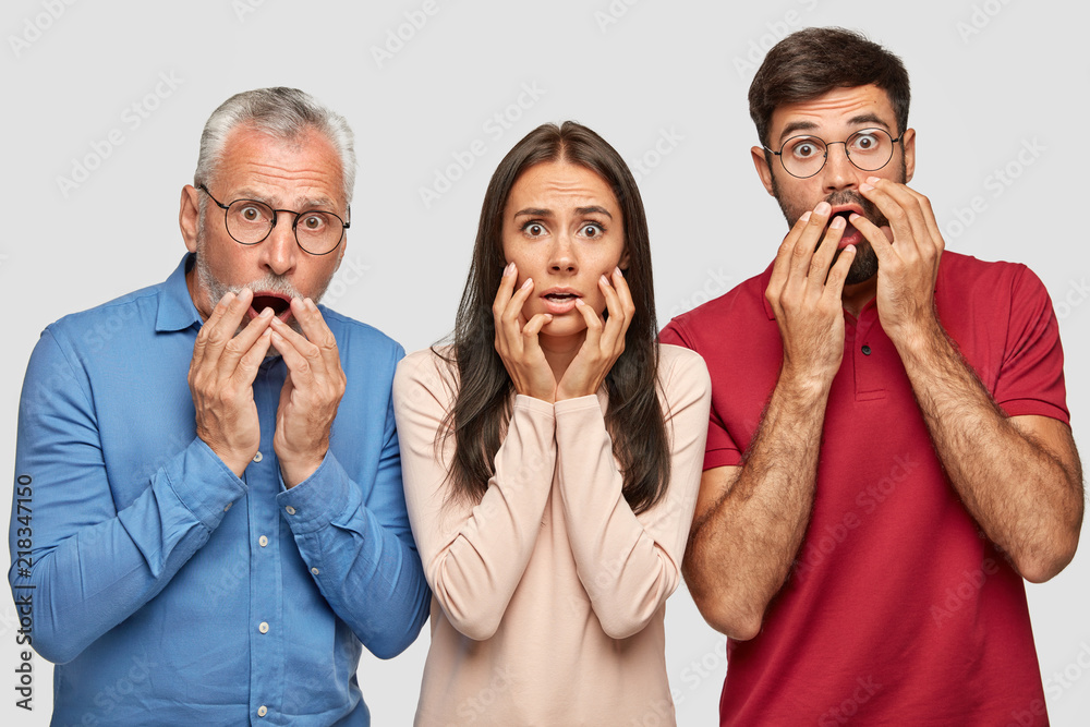 Stockfoto Three shocked people pose indoor. Surprised brother, sister and their elderly father ...