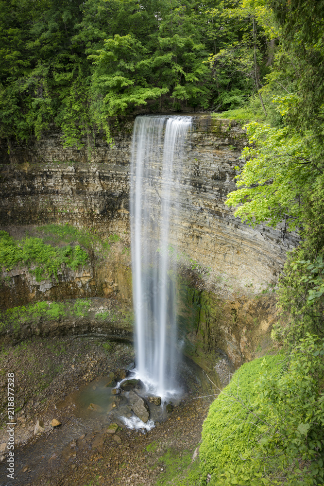 Tall ribbon waterfall flowing softly over sedimentary rock layers Stock ...