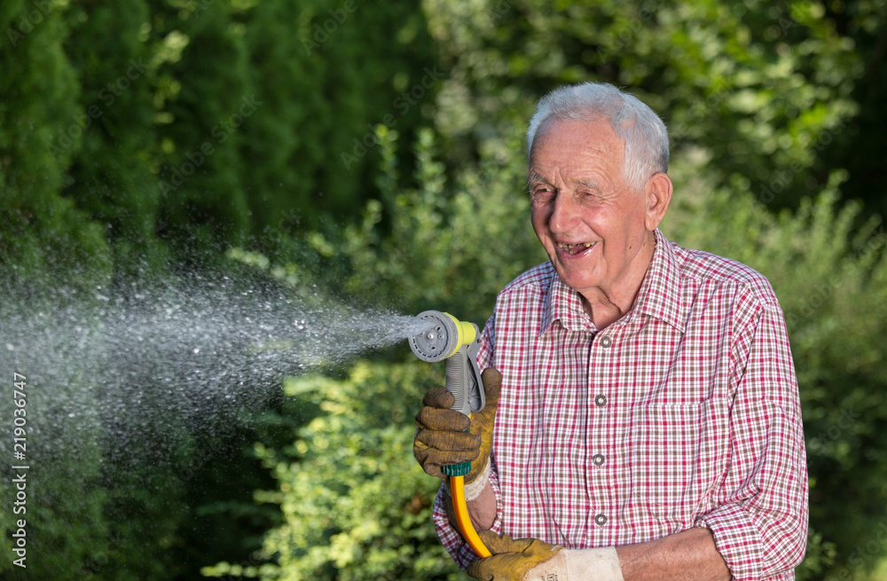Old man watering plants in garden Stock Photo | Adobe Stock