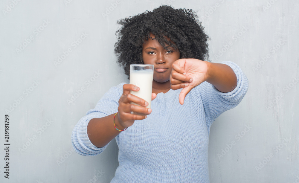 Young african american woman over grey grunge wall drinking a glass of ...