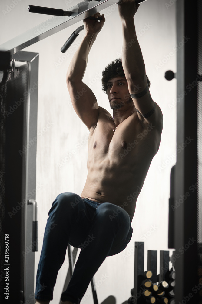 bodybuilder on the bar raises his legs up, exercises on the press in ...
