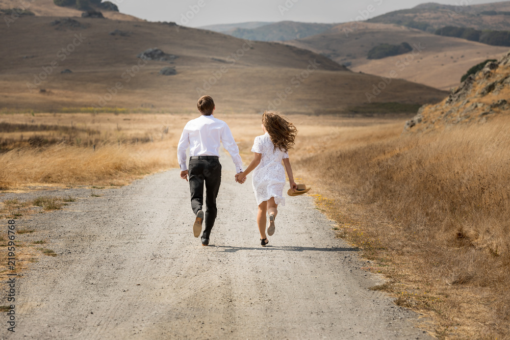 Love story. Couple holding hands and running away in mountains. Woman ...