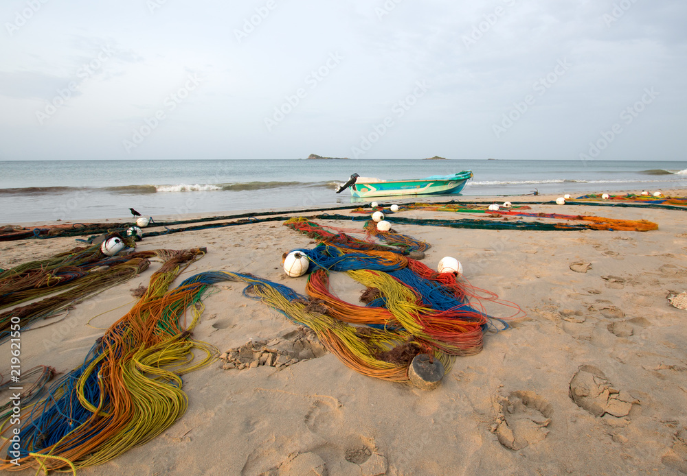 Multi-colored fishing nets drying in the sun next to small fishing boat ...