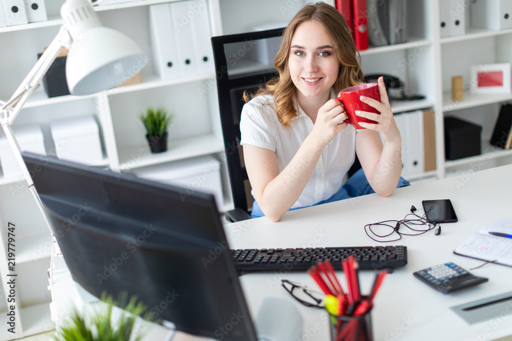 Beautiful young girl working with computer in office. The girl has a ...
