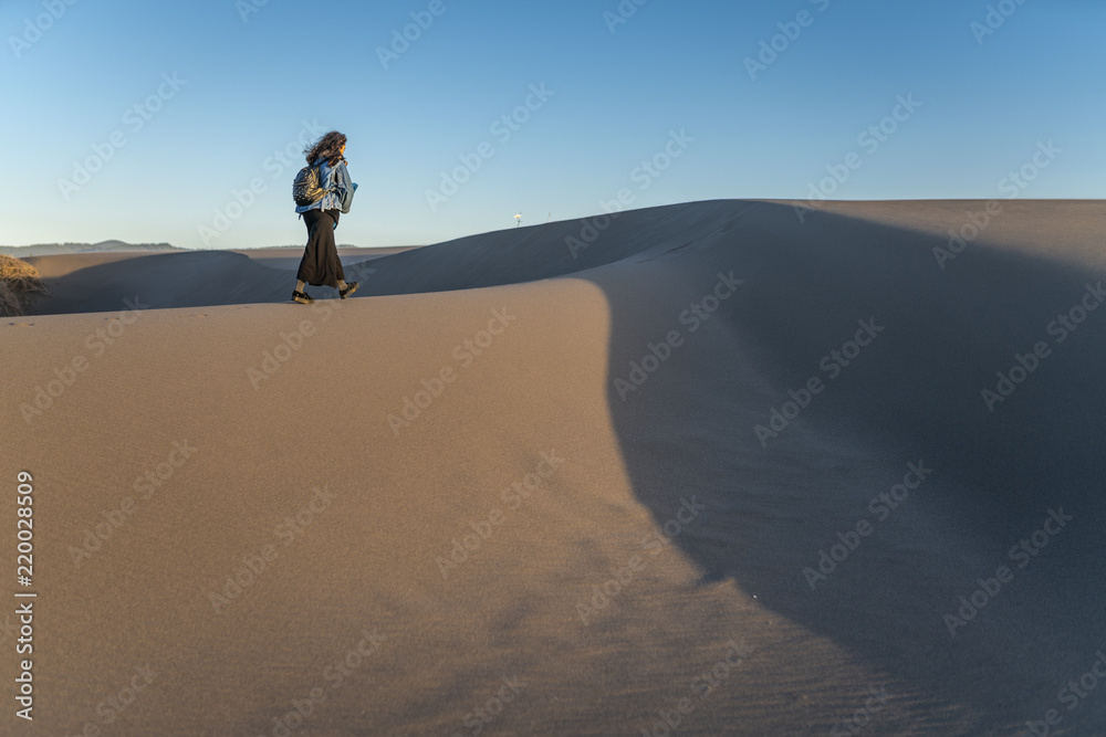 Beautiful young girl walking along the beach sand dunes step by step ...