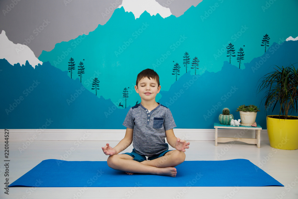 Cute caucasian boy does yoga in his room with a beautiful mountain ...