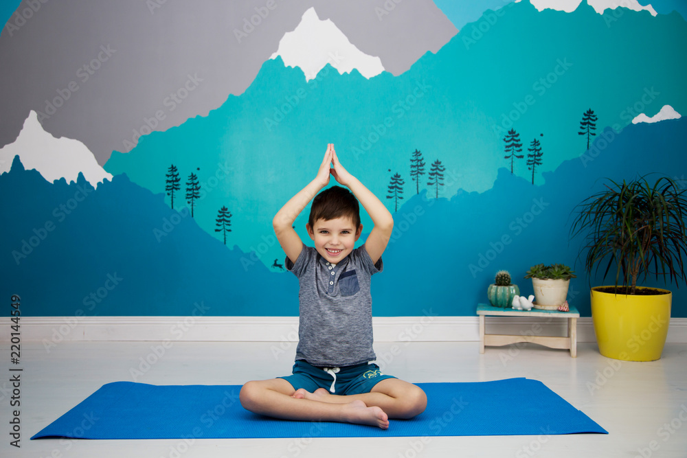 Cute caucasian boy does yoga in his room with a beautiful mountain ...