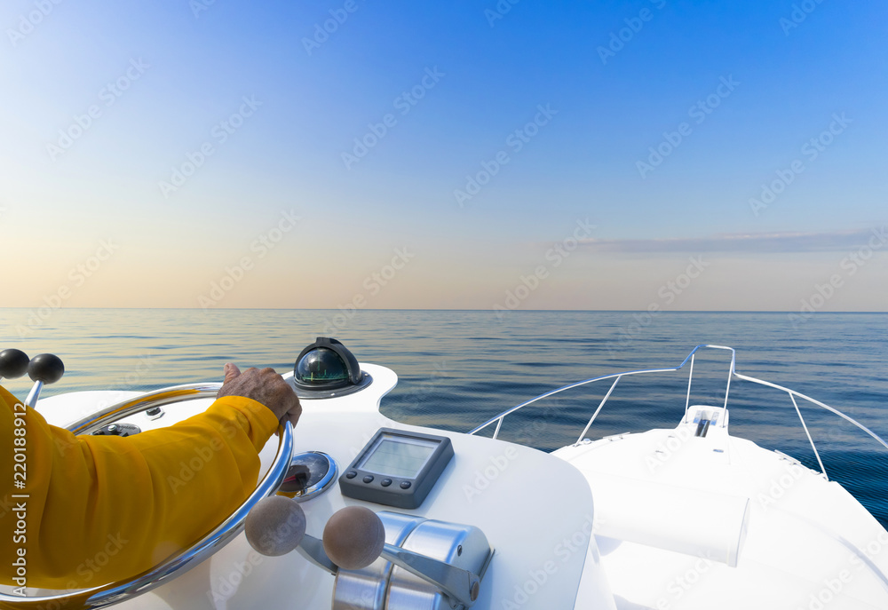 Hand of captain on steering wheel of motor boat in the blue ocean ...