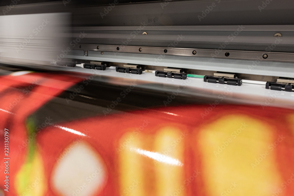 Big professional large scale printer, processing a glossy sheet of ...
