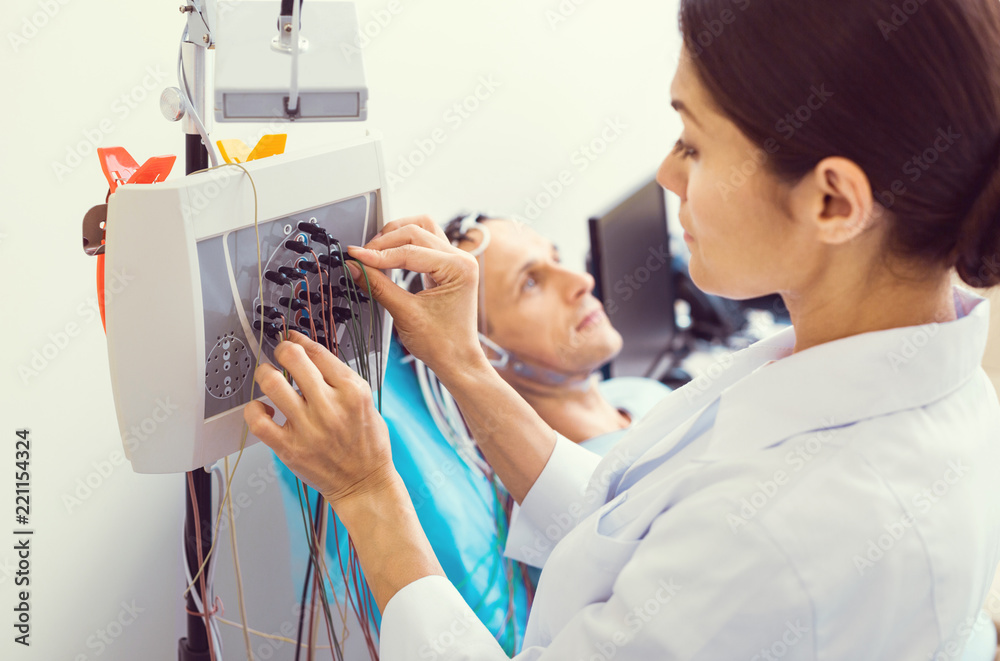 Almost ready. Young laboratory worker adjusting an electroencephalograph before analyzing her ...
