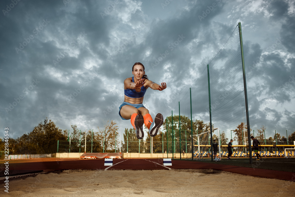 Female athlete performing a long jump during a competition at stadium ...