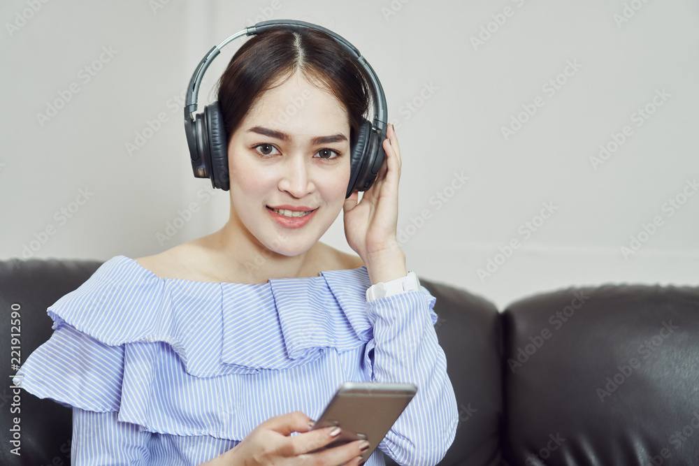 Women are listening to music from black headphones. In a comfortable ...