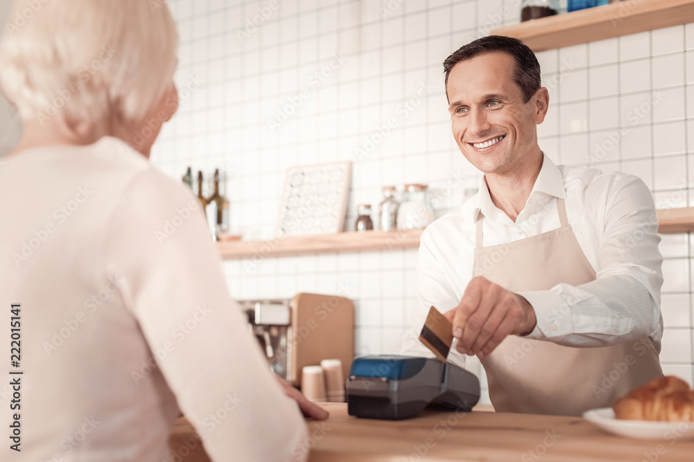 Money transaction. Delighted cheerful man using a credit card while ...