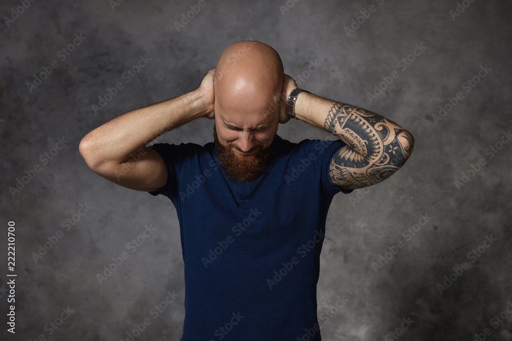 Fotografie Studio portrait of annoyed angry bald guy with tattoo ...