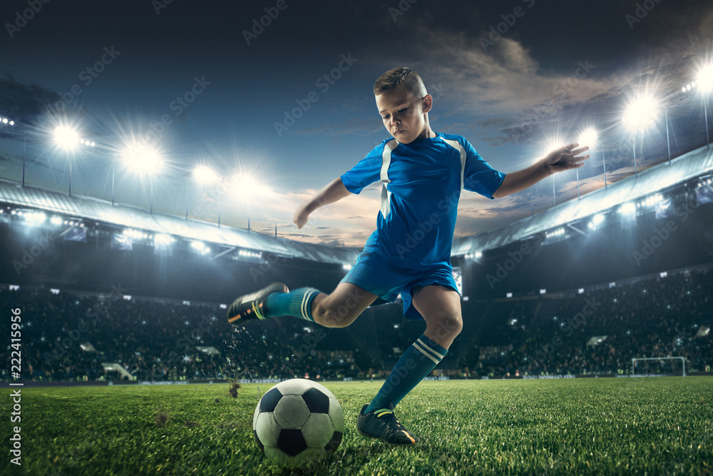 Foto de Stock Young boy with soccer ball doing flying kick at stadium ...