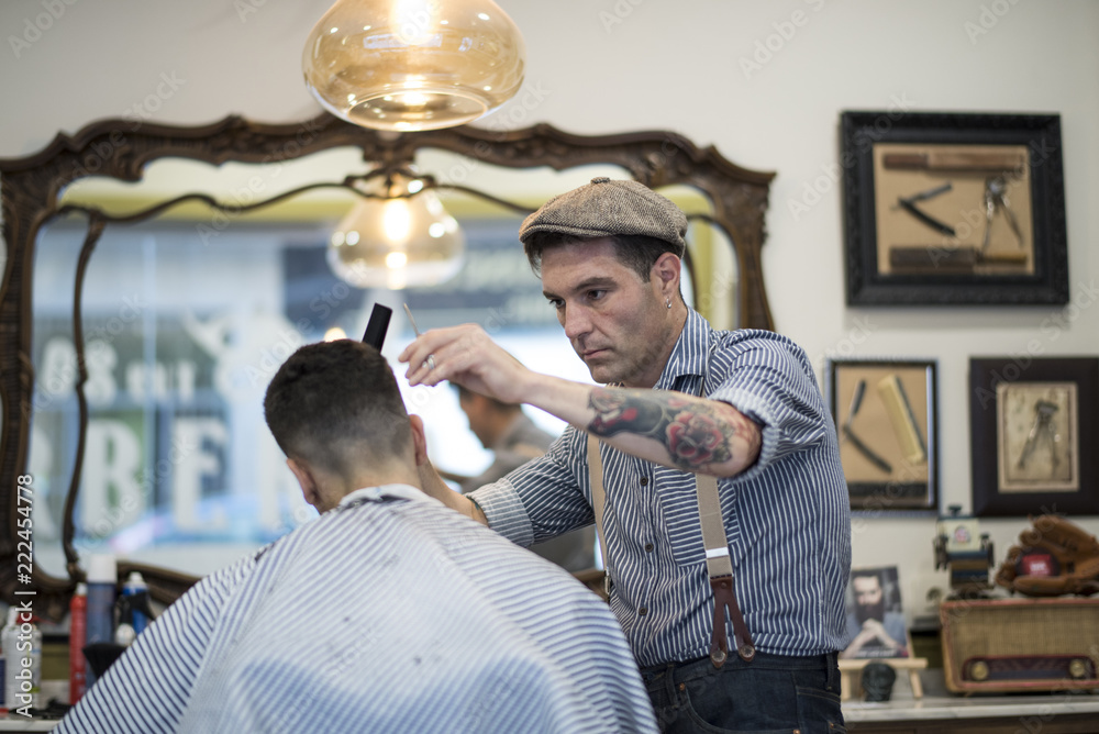 Barbero moderno con vestimenta vintage corta el pelo a joven muchacho ...