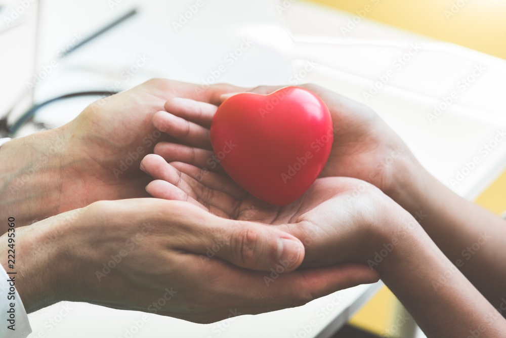 Doctor hands holding and giving red massage heart to patient little ...
