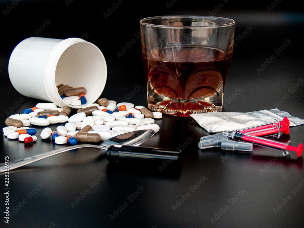 Pills of different sizes, shapes and colors, a glass of whiskey, drugs ...