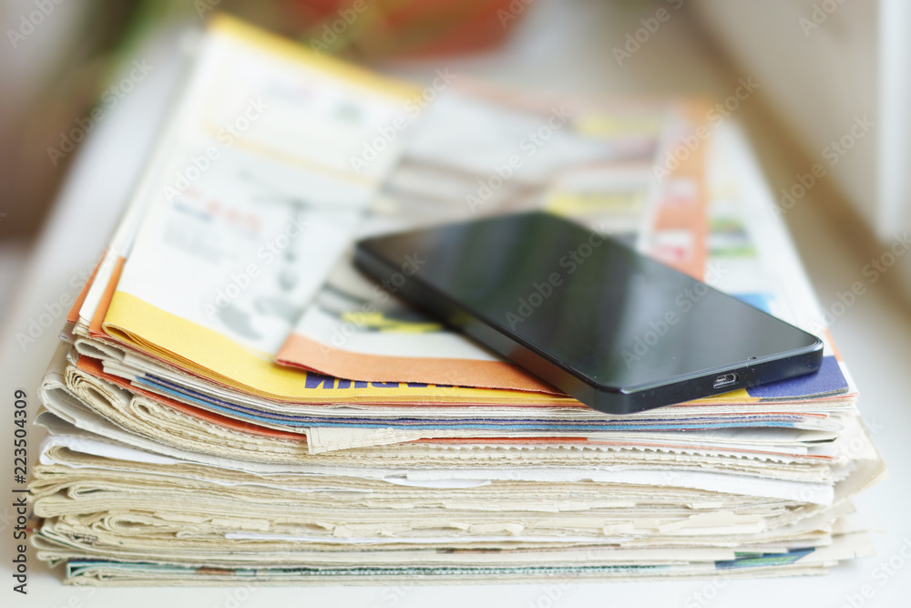 Stack of newspapers and magazines and smartphone. Pile of papers with ...
