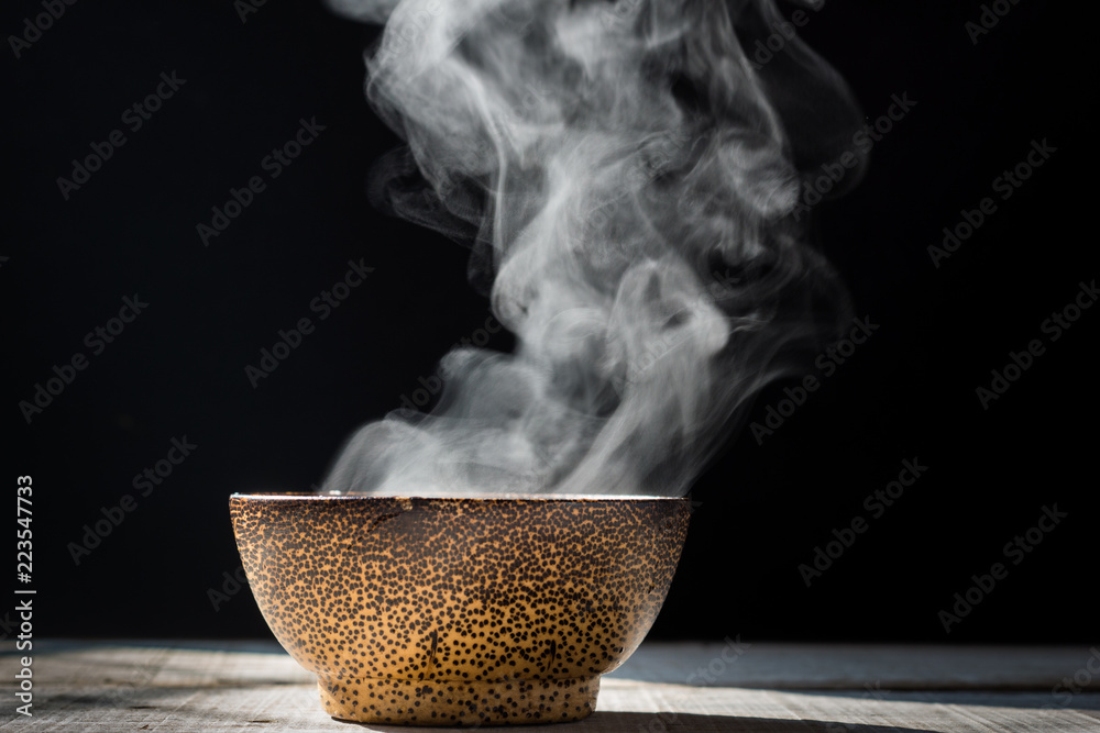 Steam of hot soup with smoke in a soup black ceramic bowl on dark ...