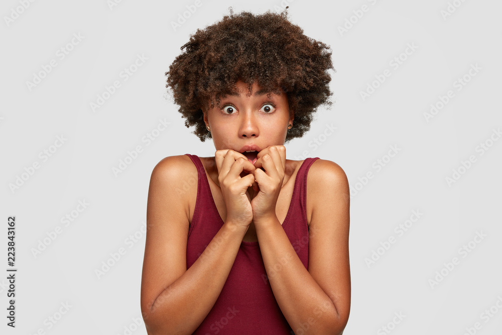 Scared dark skinned girl stares with eyes full of fear, looks anxiously ...