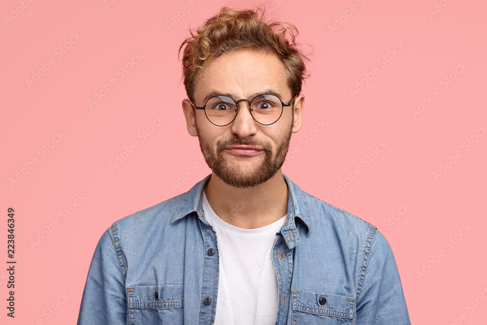 Funny man makes grimace, pouts lips, has comic facial expression, curly ...