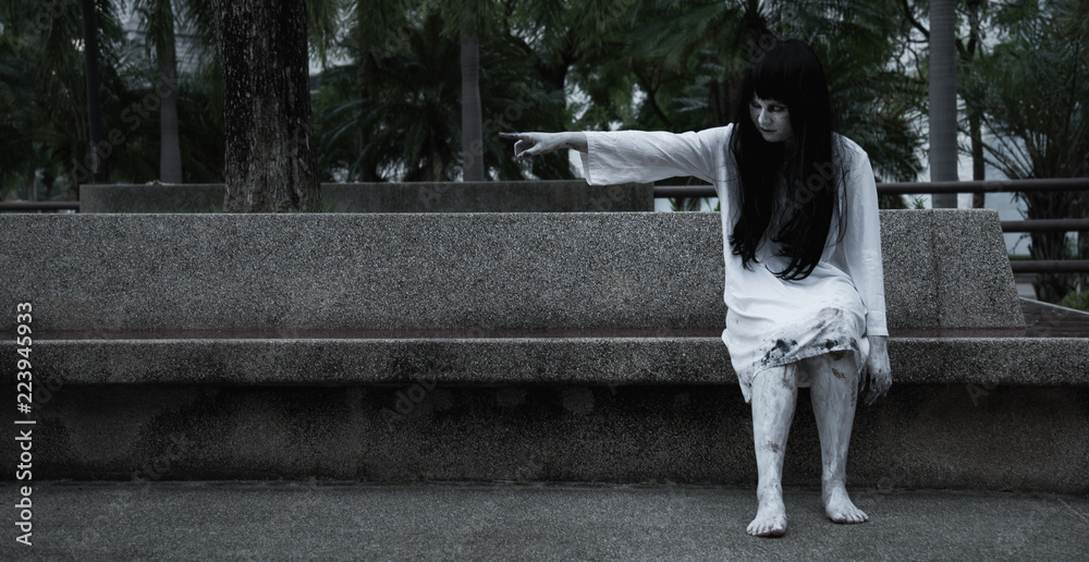 Horror woman ghost creepy sitting under tree on graden her point finger ...