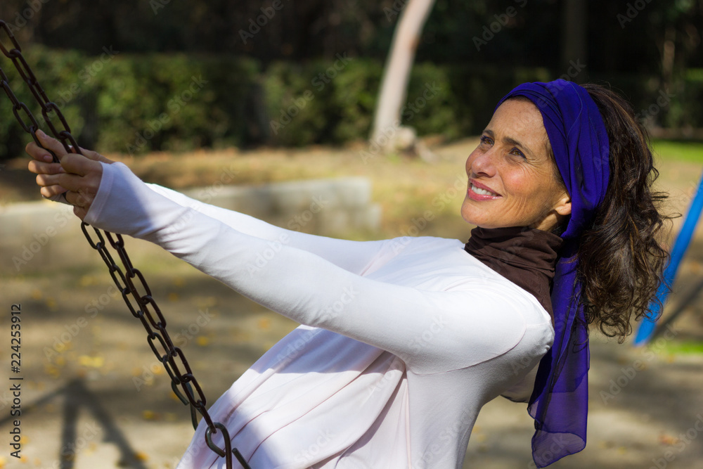 Happy beautiful woman with purple shawl on head swinging in the ...