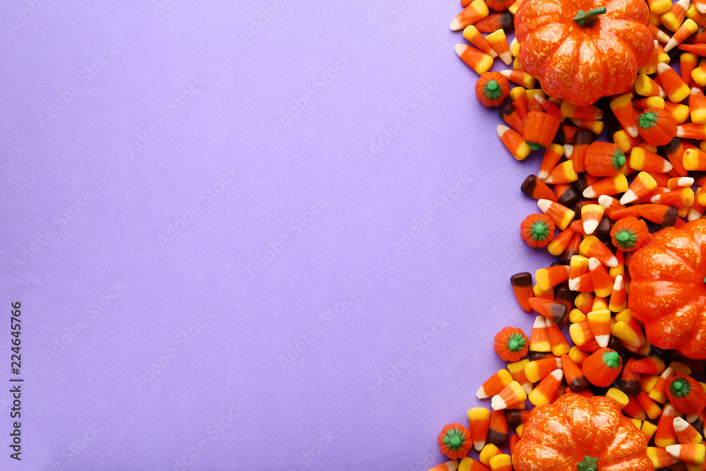 Halloween candy corns and pumpkins on purple background Stock Photo ...