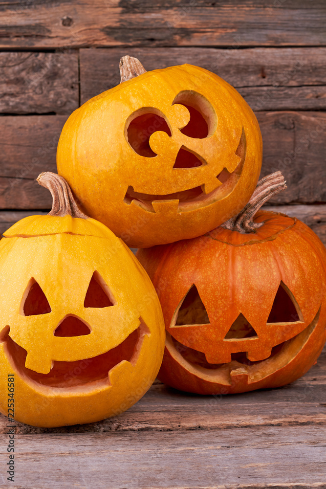 Three funny Halloween pumpkins. Funny Jack O Lntern Halloween pumpkins on wooden background. Halloween pumpkins carving ideas. Stock Photo Adobe Stock