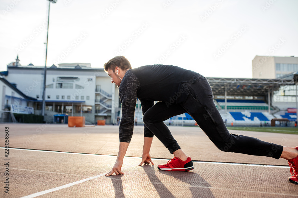 Male athlete on starting position at running track. Runner practicing ...