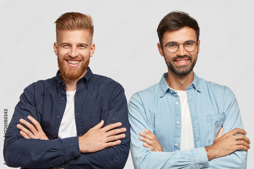 Horizontal view of cheerful friends keep hands crossed over chest ...