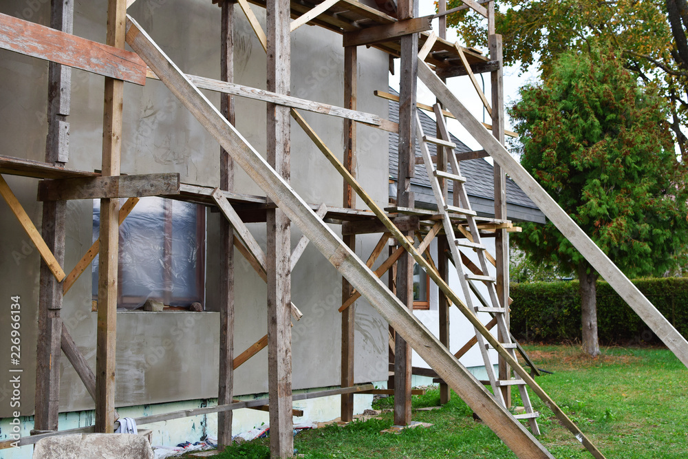 Wooden scaffolding next to unfinished residential house on facade ...