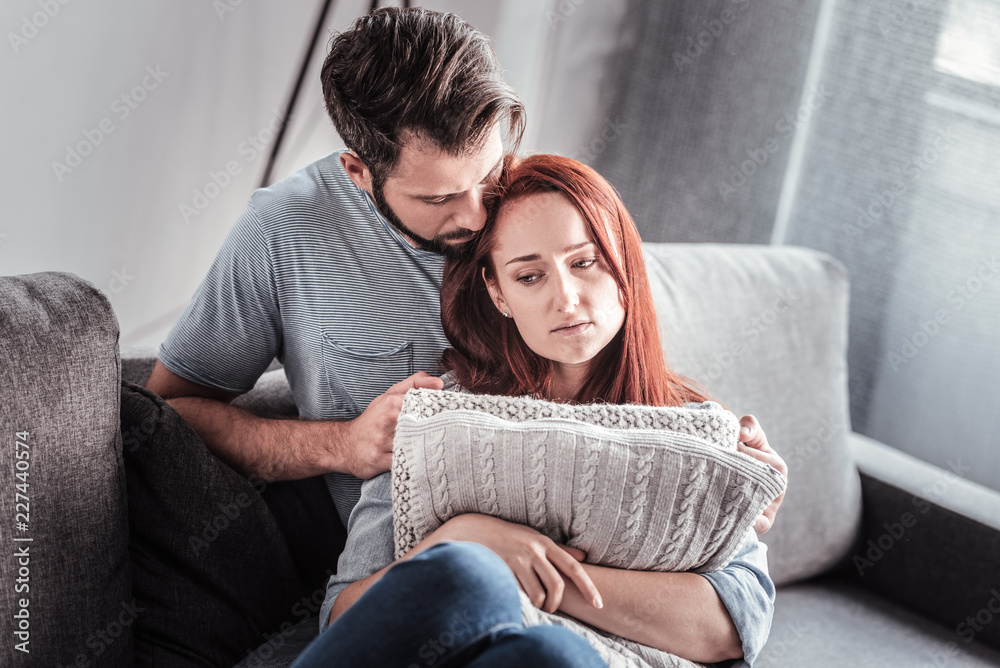 Care and support. Nice handsome caring man standing behind his wife and ...