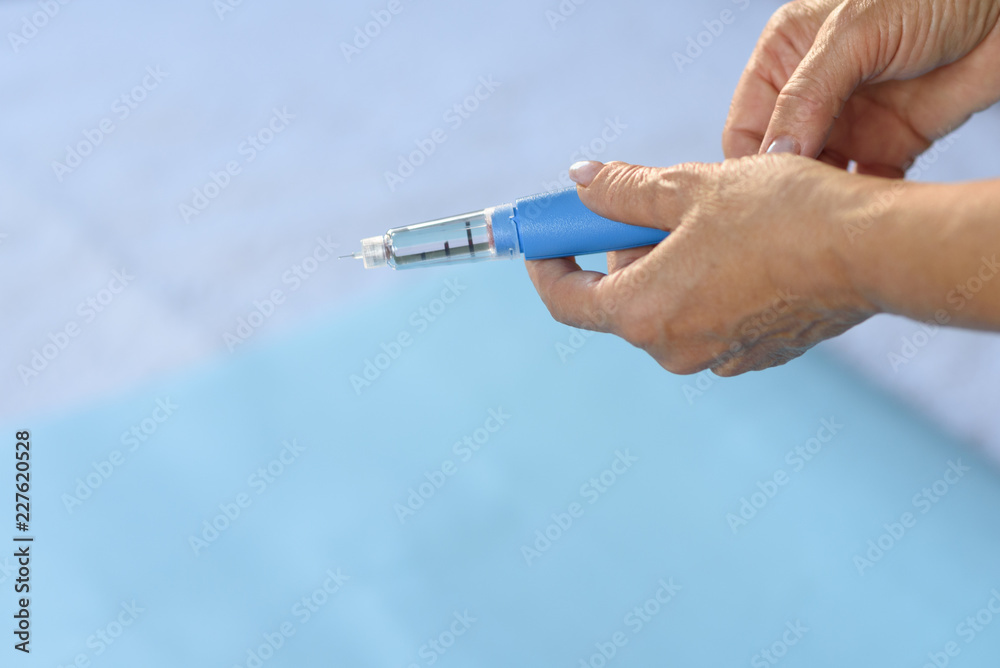 Elderly woman giving herself injection against osteoporosis in abdomen ...