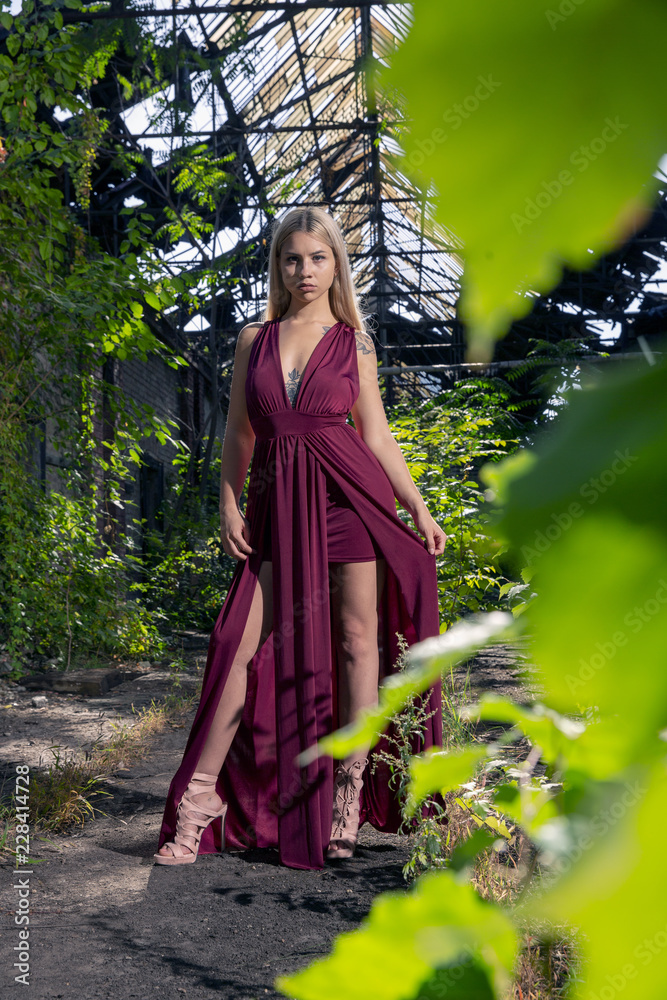 Fashion model standing and posing in red dress at the abandoned train ...