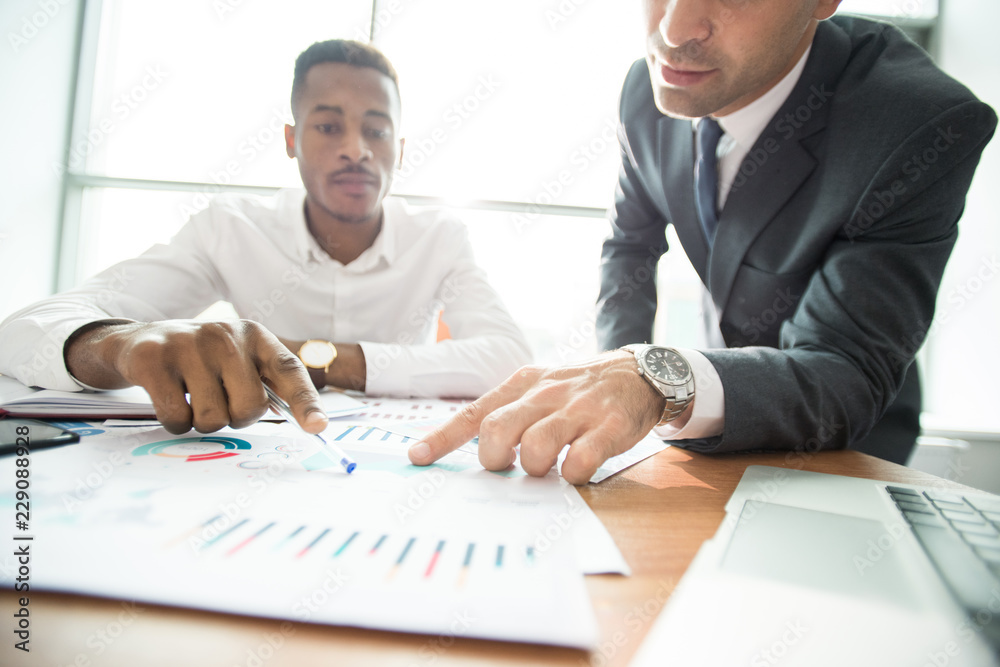 Serious concentrated African-American businessman pointing at chart ...