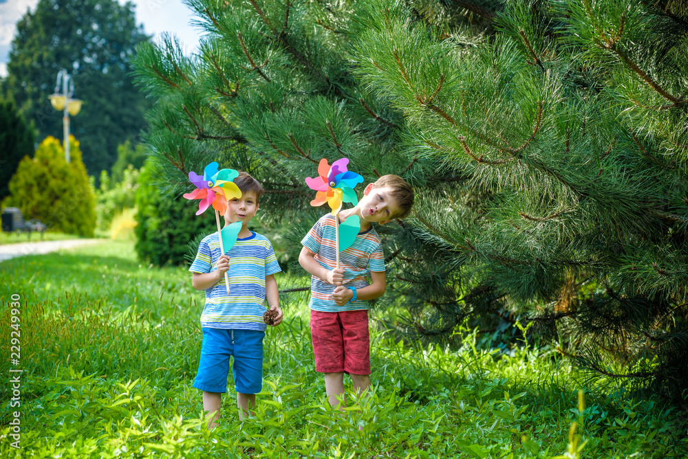 Two happy children playing in garden with windmill pinwheel. Adorable ...