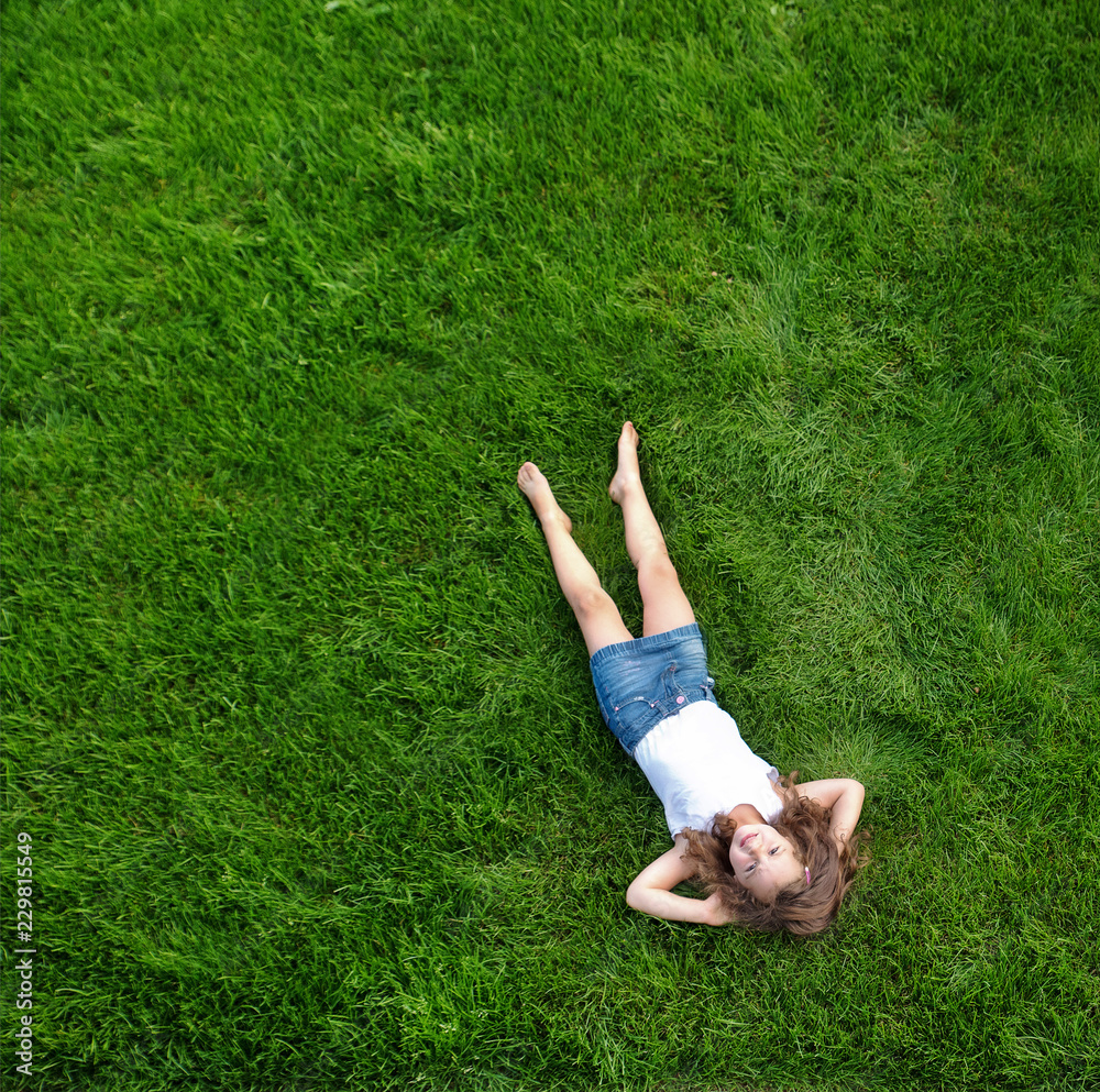 Relaxed little girl lying on a fresh, green lawn Stock Photo | Adobe Stock