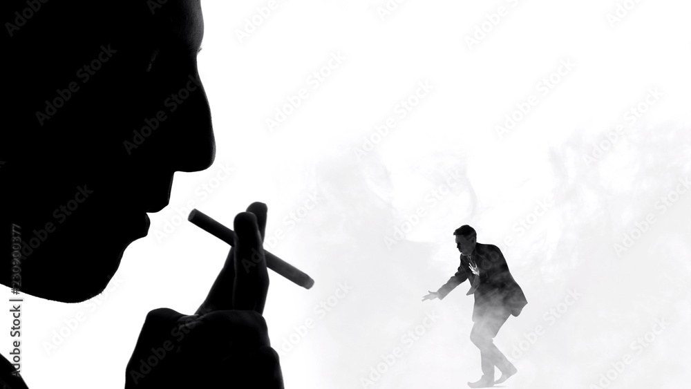 Shadow of male smoking cigarette, exhaling smoke on tiny man, harmful ...