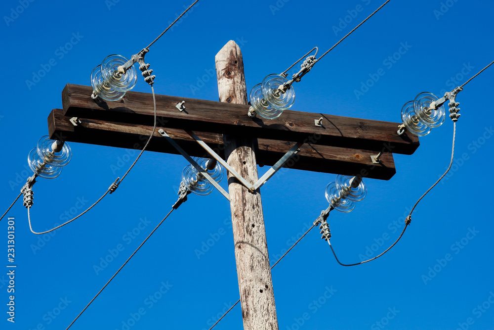 Old simple rural weathered wooden utility pole with parallel cables and ...