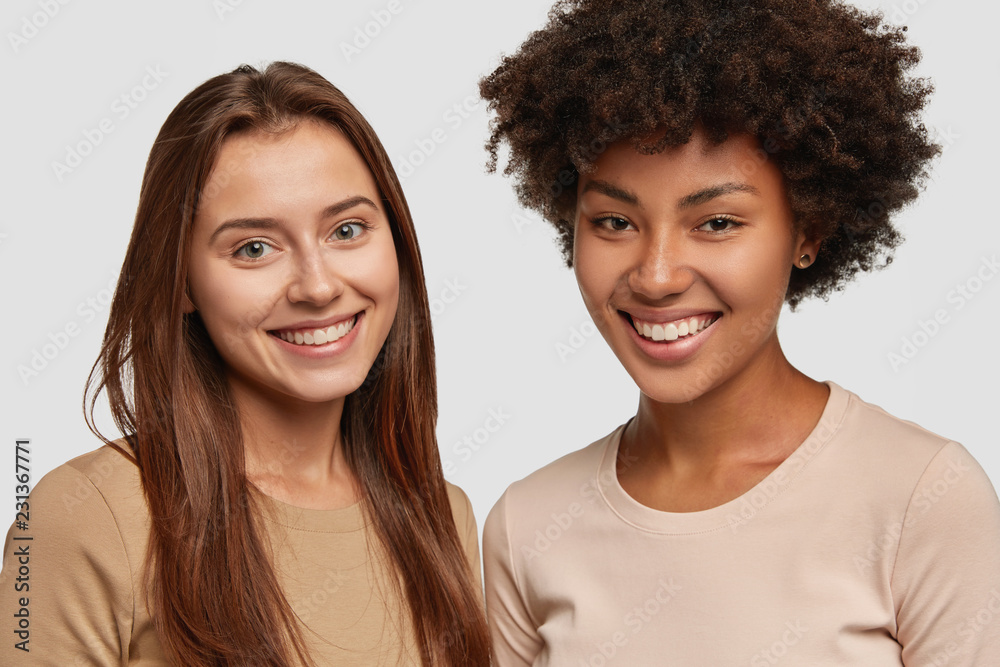 Close up shot of good looking positive two women have tender smiles on ...