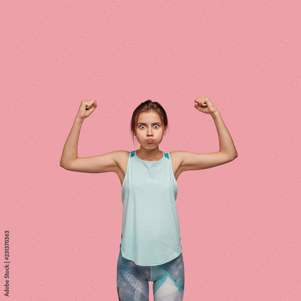 Shot of bugged eyed Caucasian lady blows cheeks, raises hands, shows ...