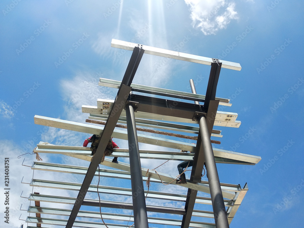 Construction workers installing metal roof trusses at the construction ...
