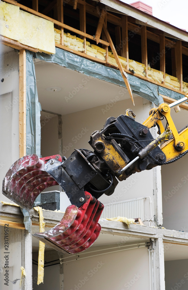 Demolition work. Excavator with grab breaking down a house. Stock Photo ...
