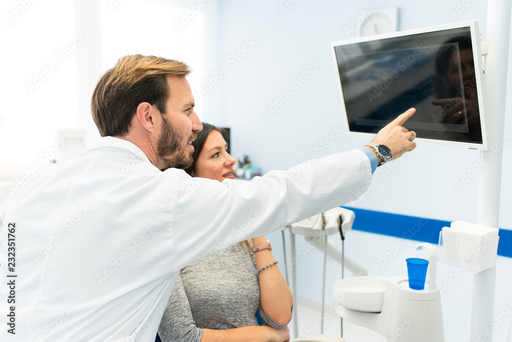 Young handsome dentist working in an ambulant, showing his female ...
