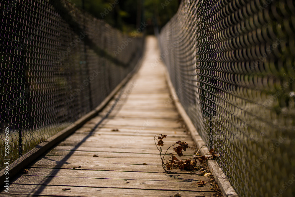 Suspension bridge over the river, lined with wooden boards, mesh ...