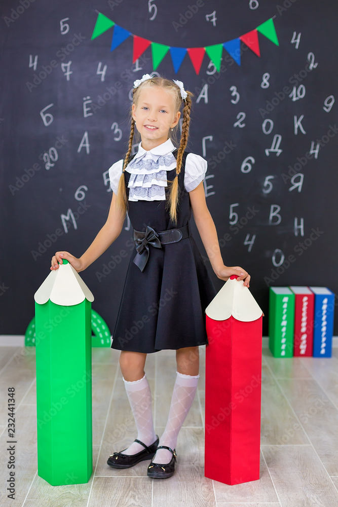 The schoolgirl in school uniform with books and textbooks is on a light ...
