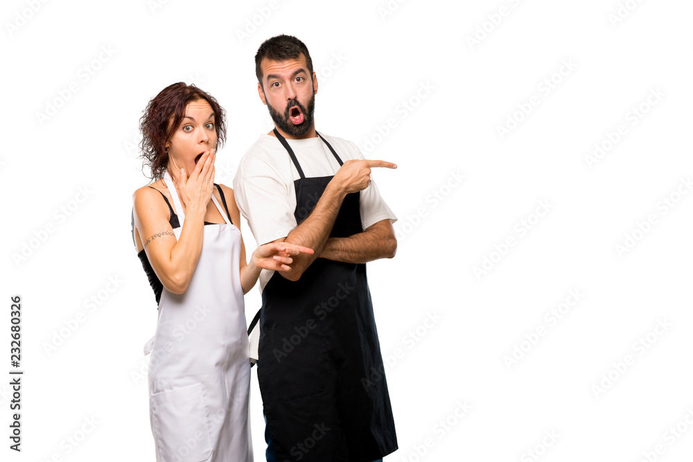 Couple of cooks pointing finger to the side with a surprised fac on ...