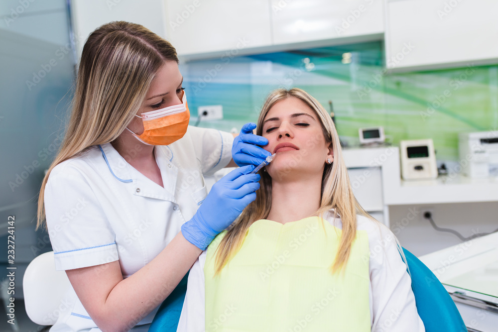 Beautiful young woman gets botox injection in her lips. Woman in beauty ...
